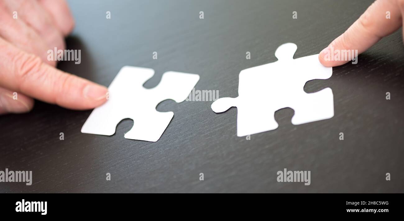 Hands joining two puzzle pieces, teamwork concept Stock Photo - Alamy