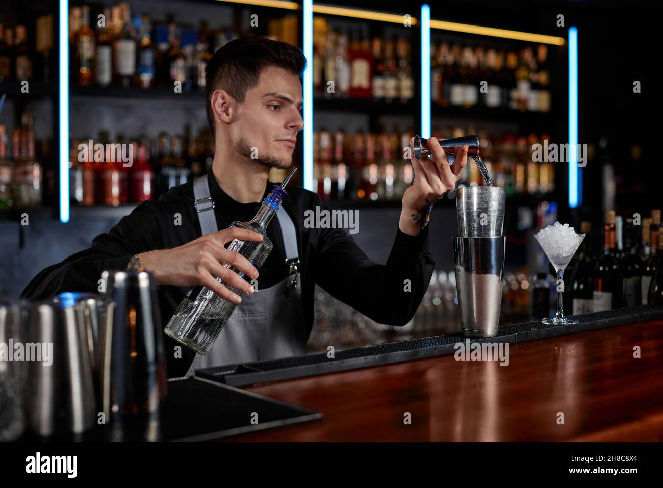 Bartender in apron adds ingredient to shaker Stock Photo - Alamy