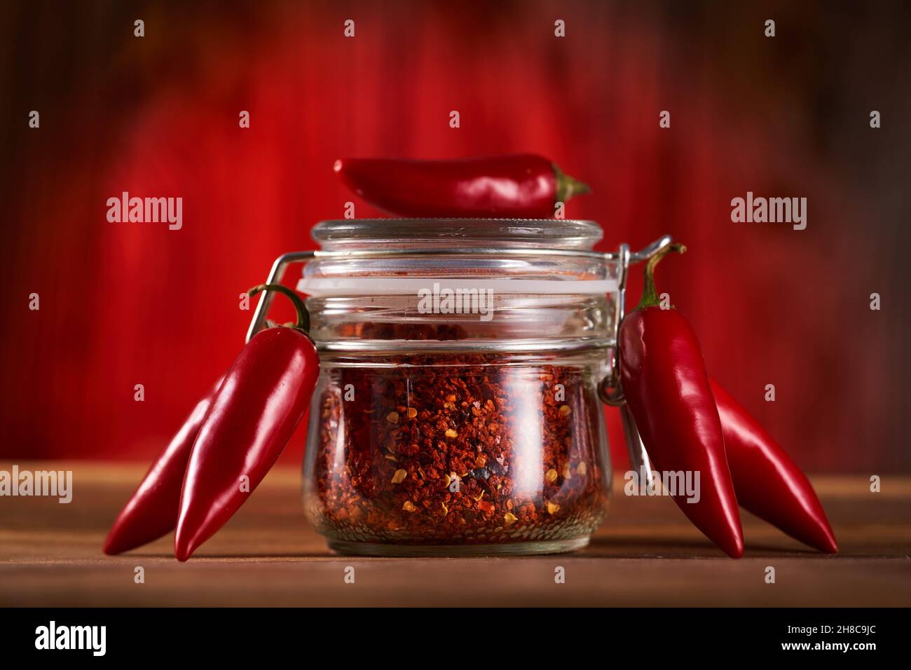 Hot chili raw and pepper flakes in a jar on a wooden board Stock Photo ...