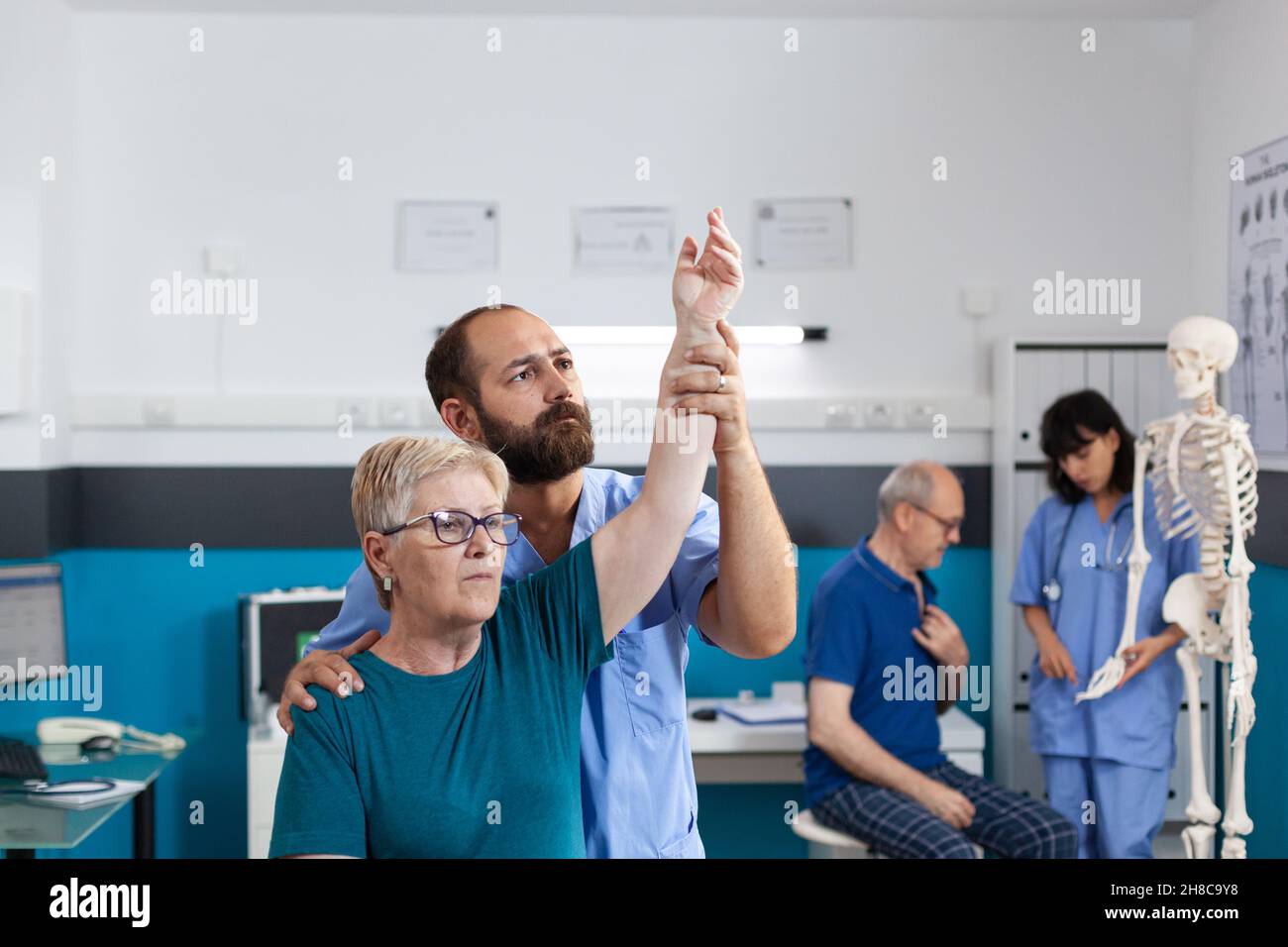 Chiropractor holding arm of old woman to relieve pressure for recovery ...