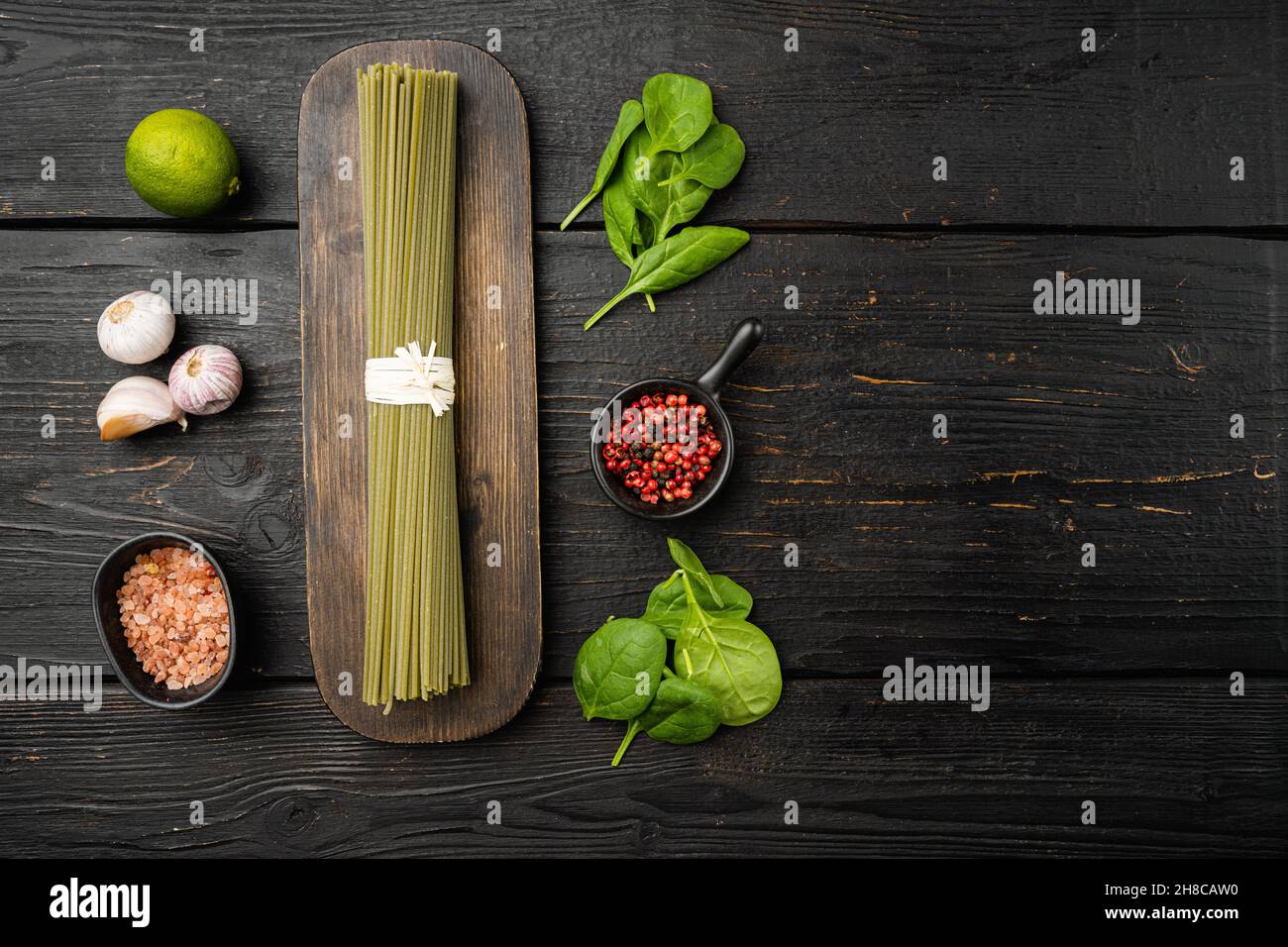 Raw dry green spaghetti with spinach set, on black wooden table ...