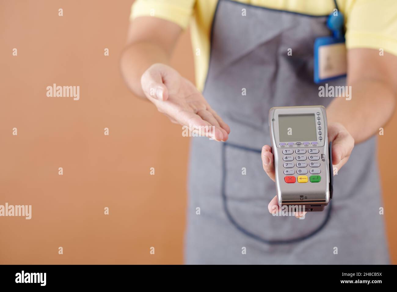 Hands of waiter offering payment terminal to customer paying for lunch ...