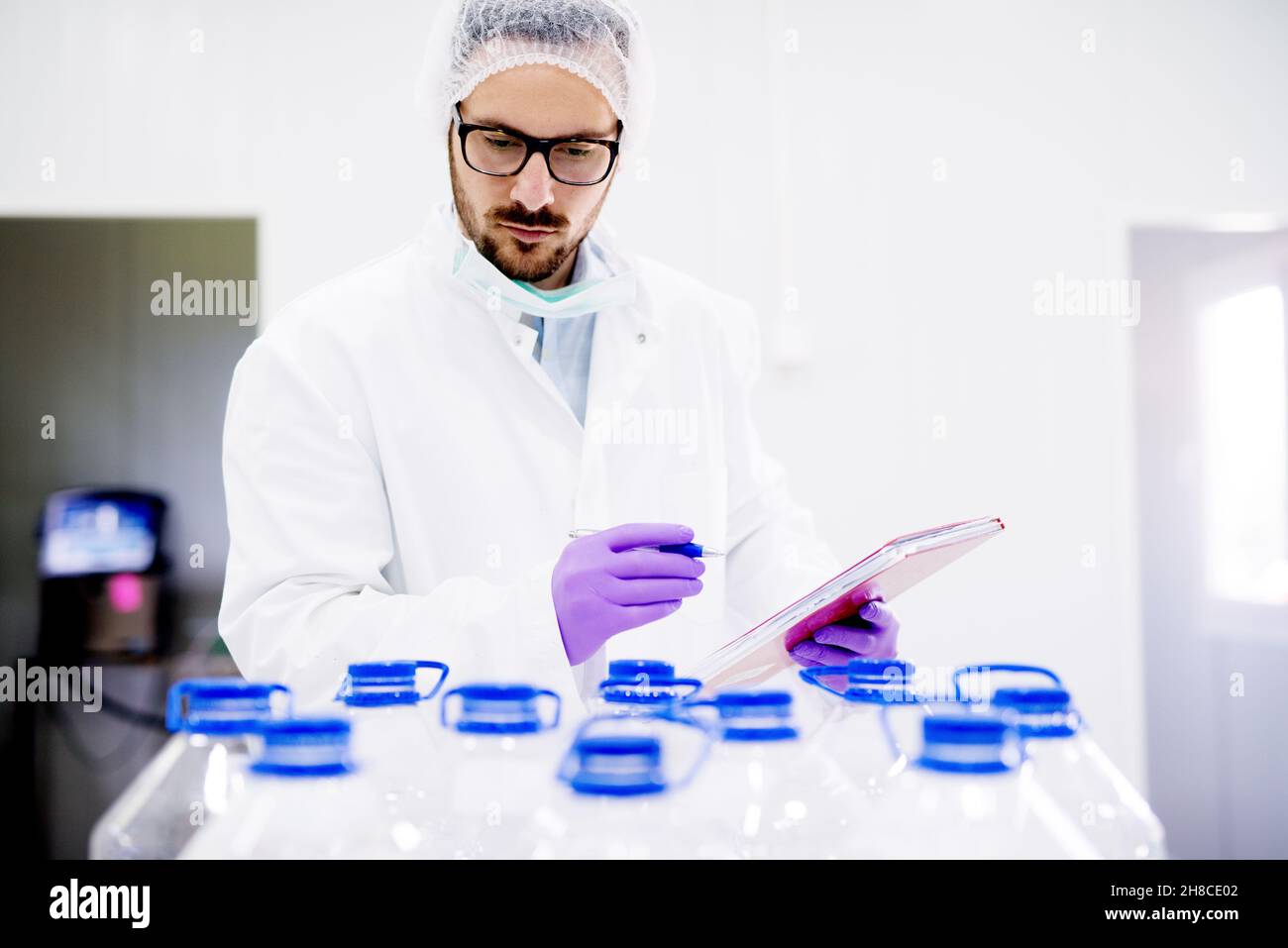 Chemist doing quality control of bottled water. Checking whether it ...