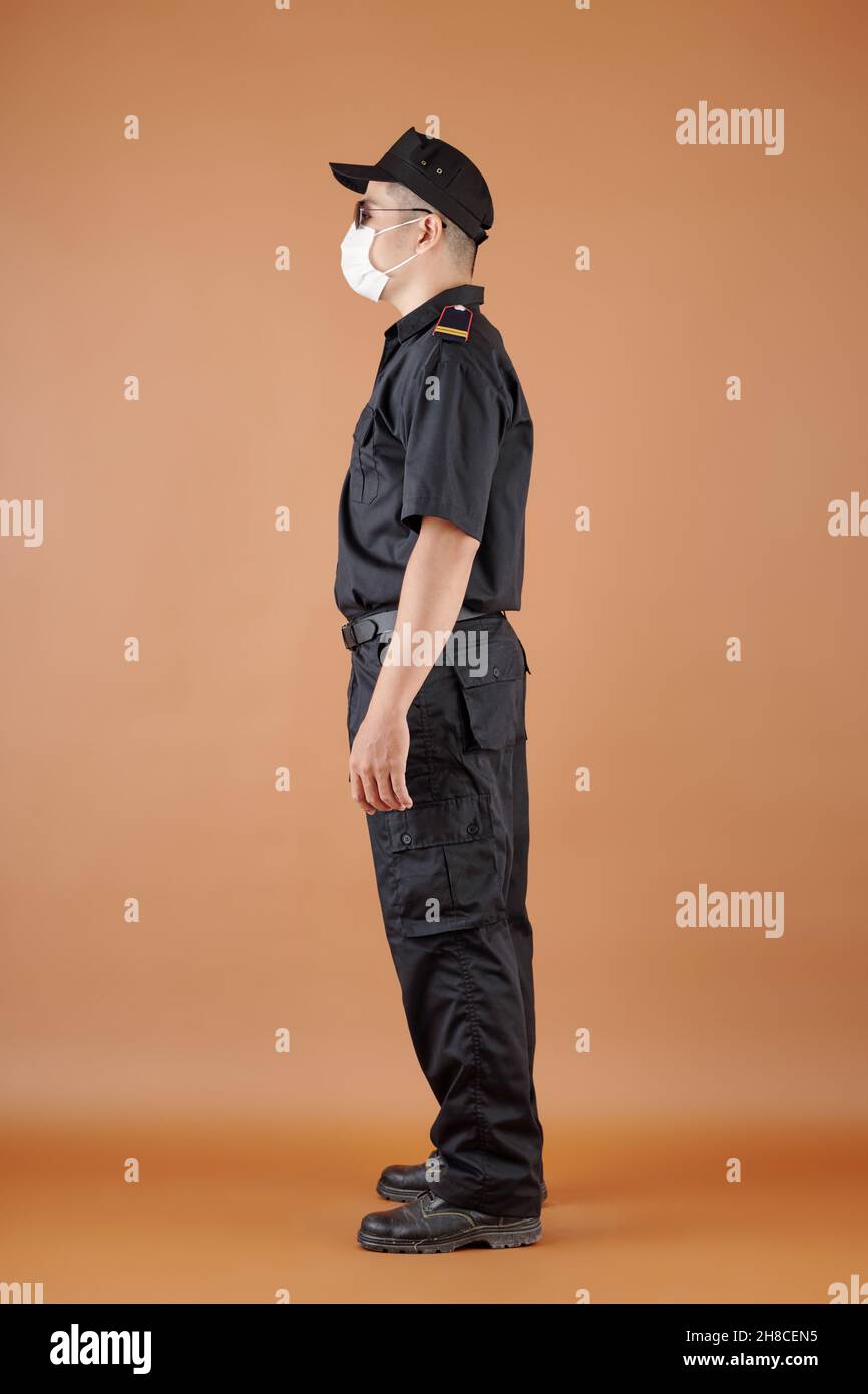 Side view of policeman in black uniform, sunglasses and medical mask ...