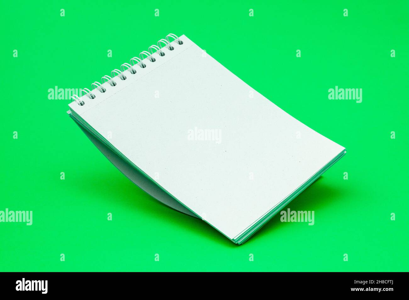 Blank spiral notebook falling on the green background. Copy space Stock ...