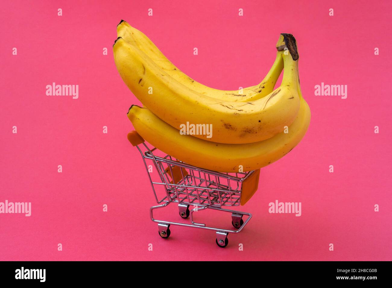 Shopping cart full of bananas on pink background Stock Photo - Alamy