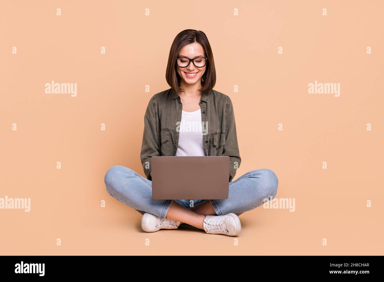 Photo of cheerful positive programmer lady sit floor hold pc wear ...