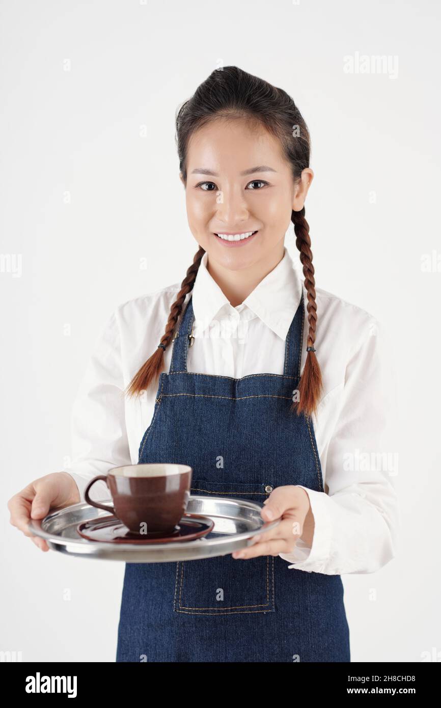 Positive young pretty waitress holding tray with cup of cappuccino ...