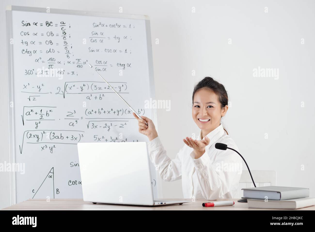 Portrait of smiling young woman teaching online math lesson and ...