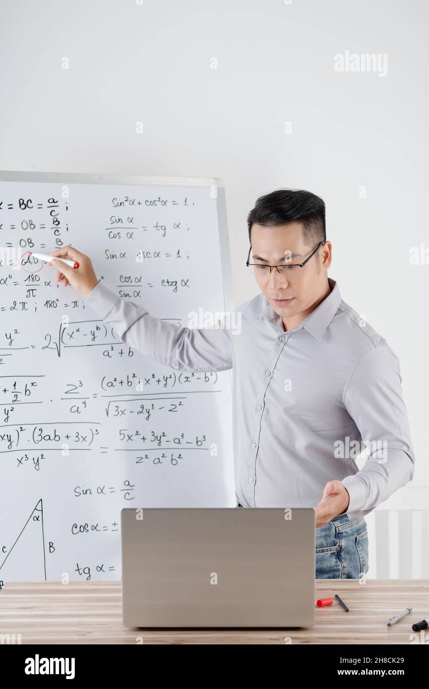 Tutor explaining math topic to student during online class, he is ...