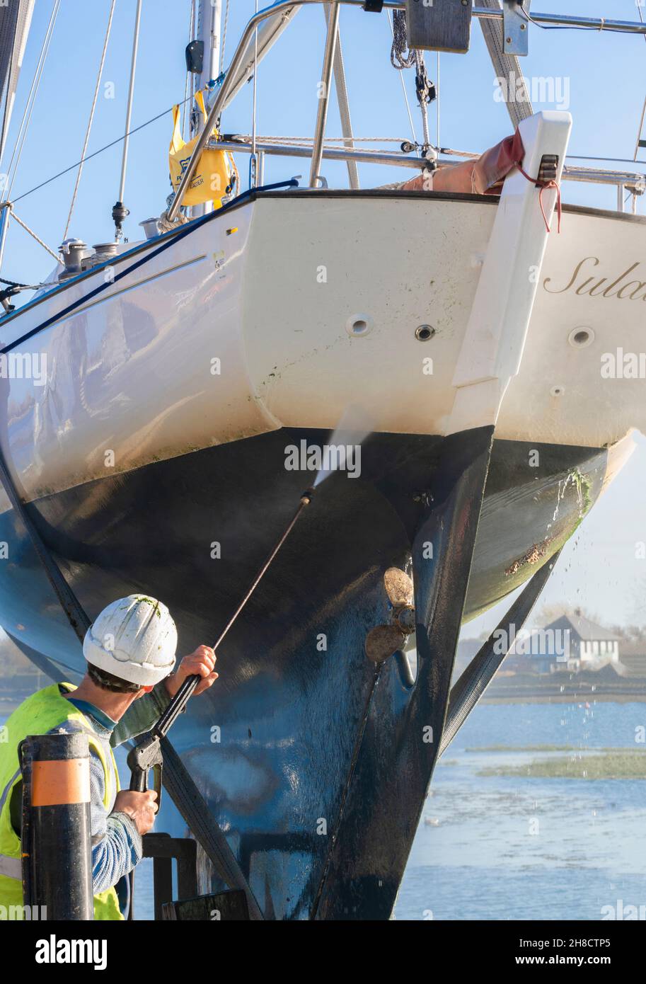 Yacht (Contessa 26)in crane slings at Bosham Quay being jet washed to ...