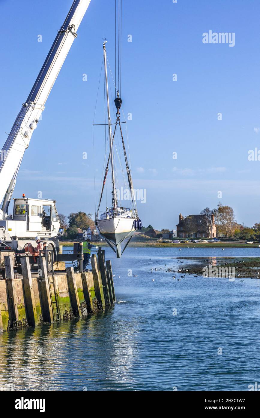 Yacht (Contessa 26)in crane slings at Bosham Quay being jet washed to ...