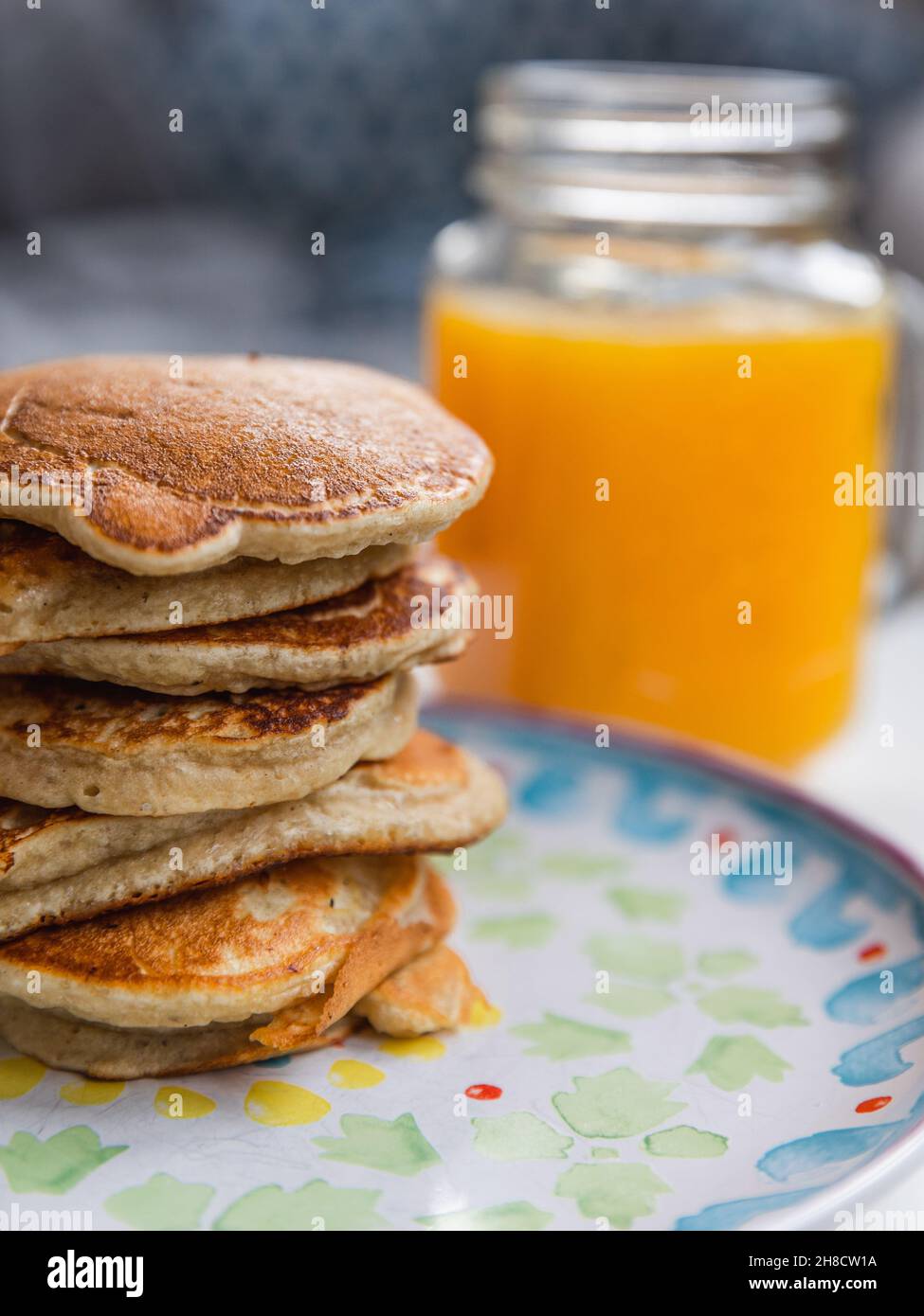 Vertical shot of a stack of pancakes and a glass of fresh orange juice ...