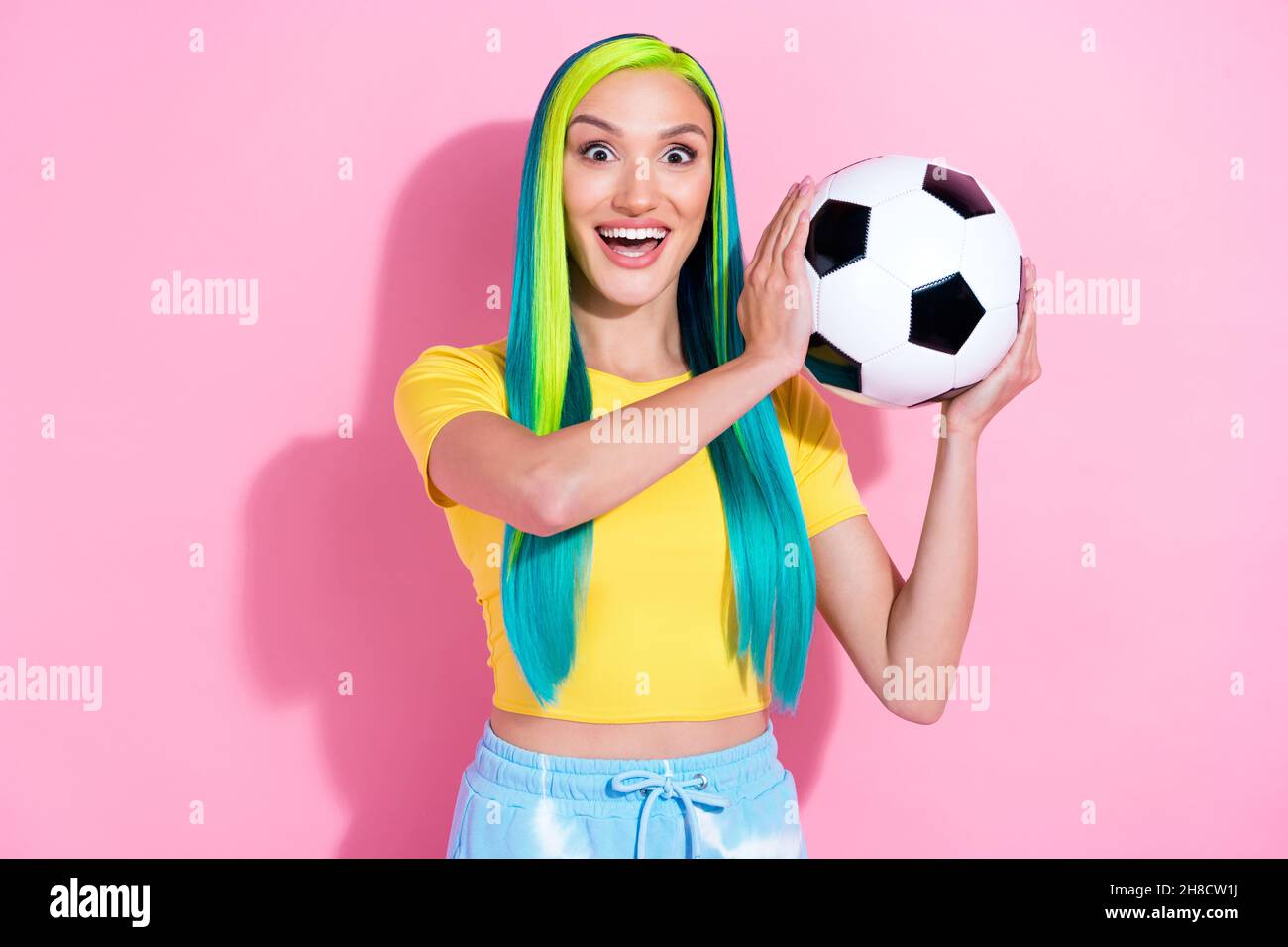 Photo of young beautiful amazed female catch football ball sportive ...