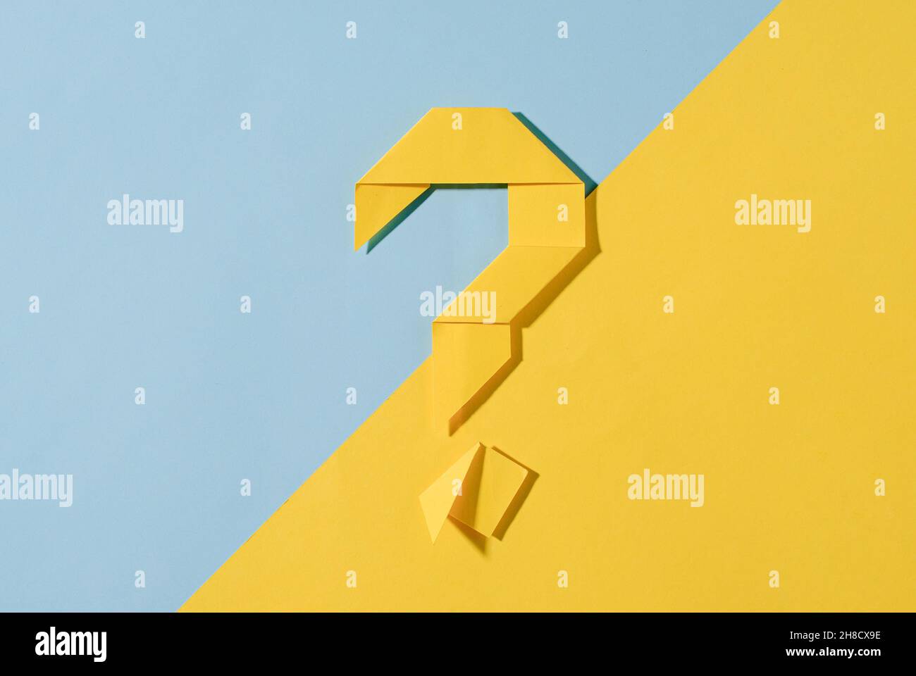 Yellow origami question mark on a diagonal two tone background of ...