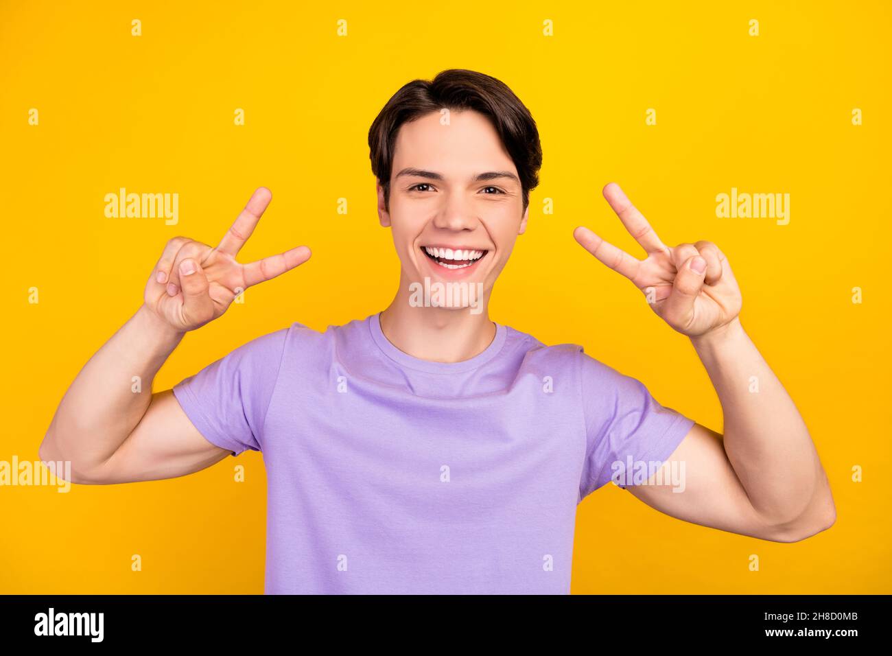 Photo of excited positive guy show two v-signs have fun wear purple t ...