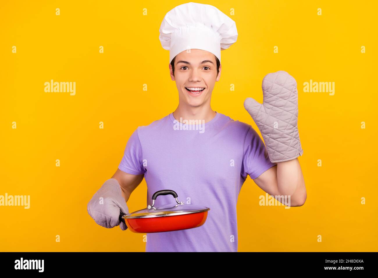 Portrait of attractive cheerful guy frying fresh meal waving hi ...