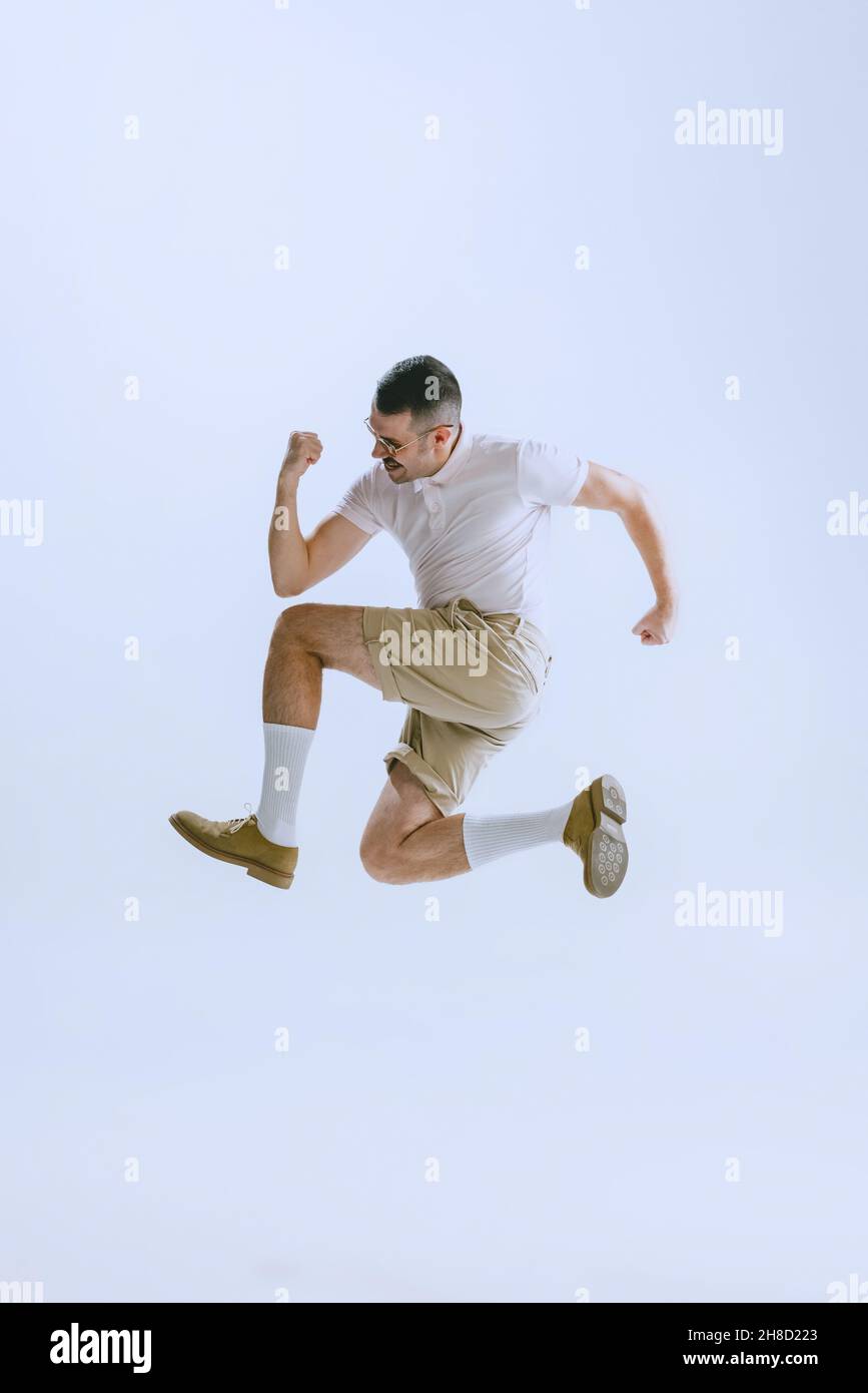 Dynamic portrait of young man dressed in 50s, 60s style jumping high ...