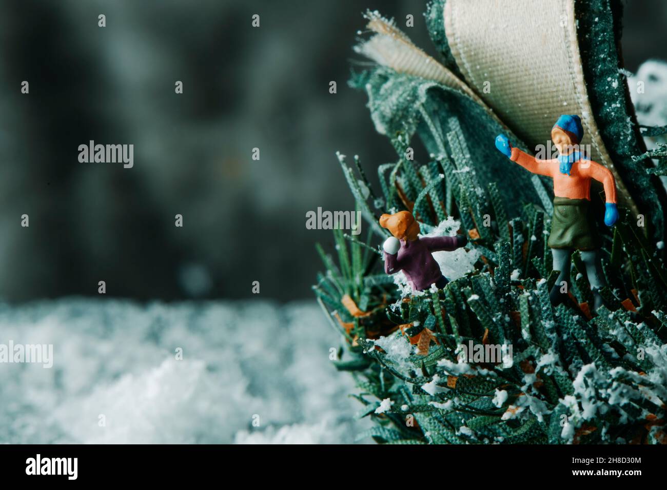 closeup of some miniature people playing with the fake snow, with some ...