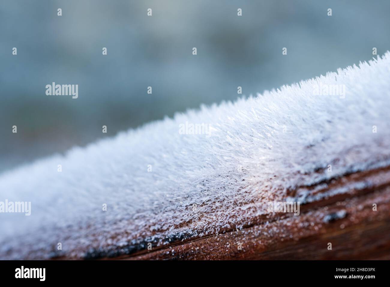 Wooden pole covered with natural structure of ice crystals, lit by ...