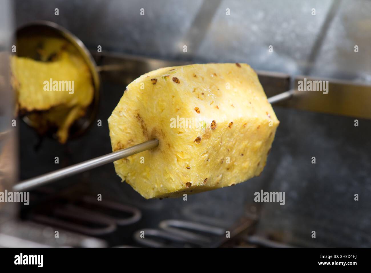 Pineapple is cooked on skewer on electric grill Stock Photo - Alamy