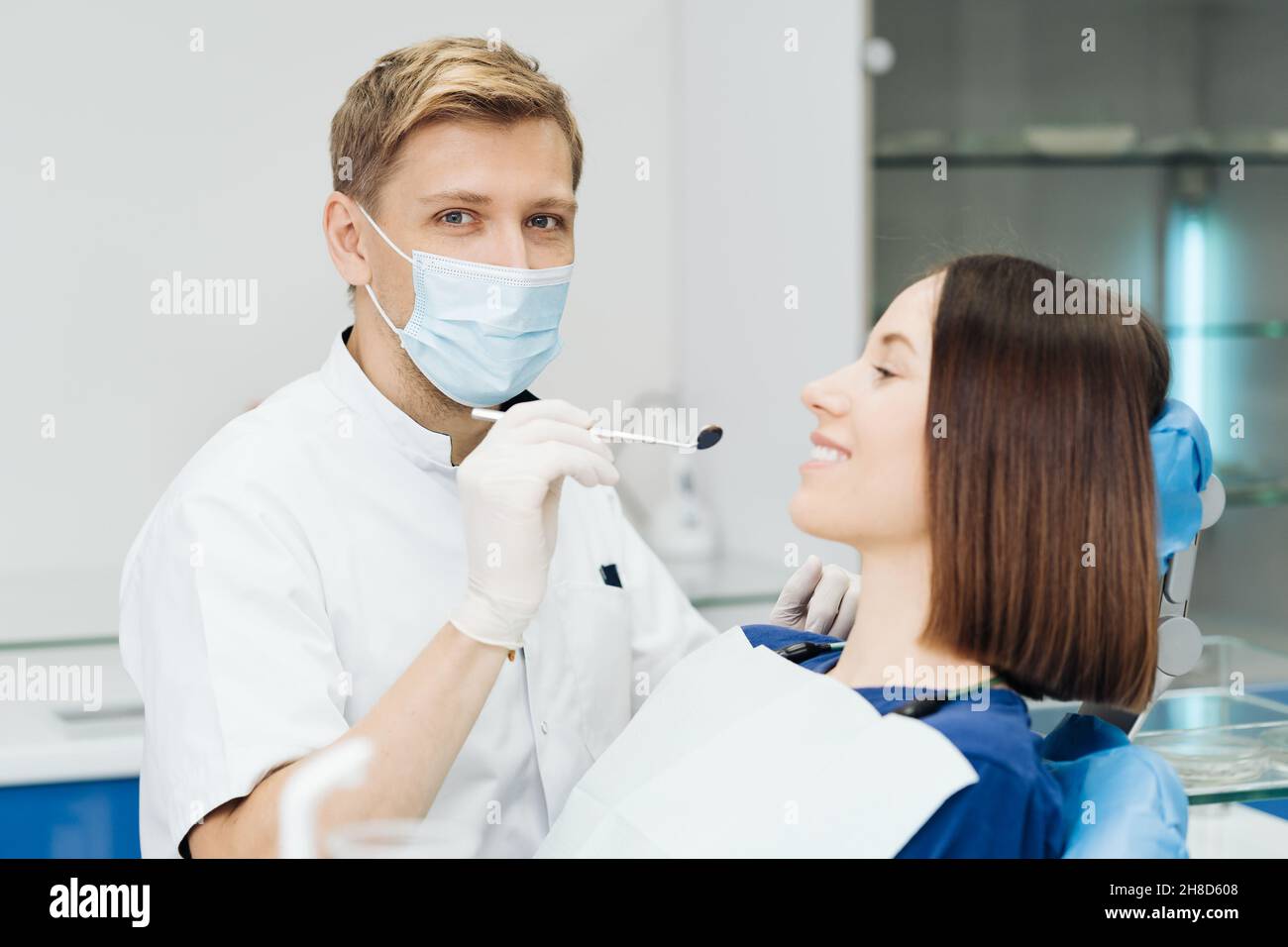 Caucasian male dentist examining young woman patient's teeth at dental ...