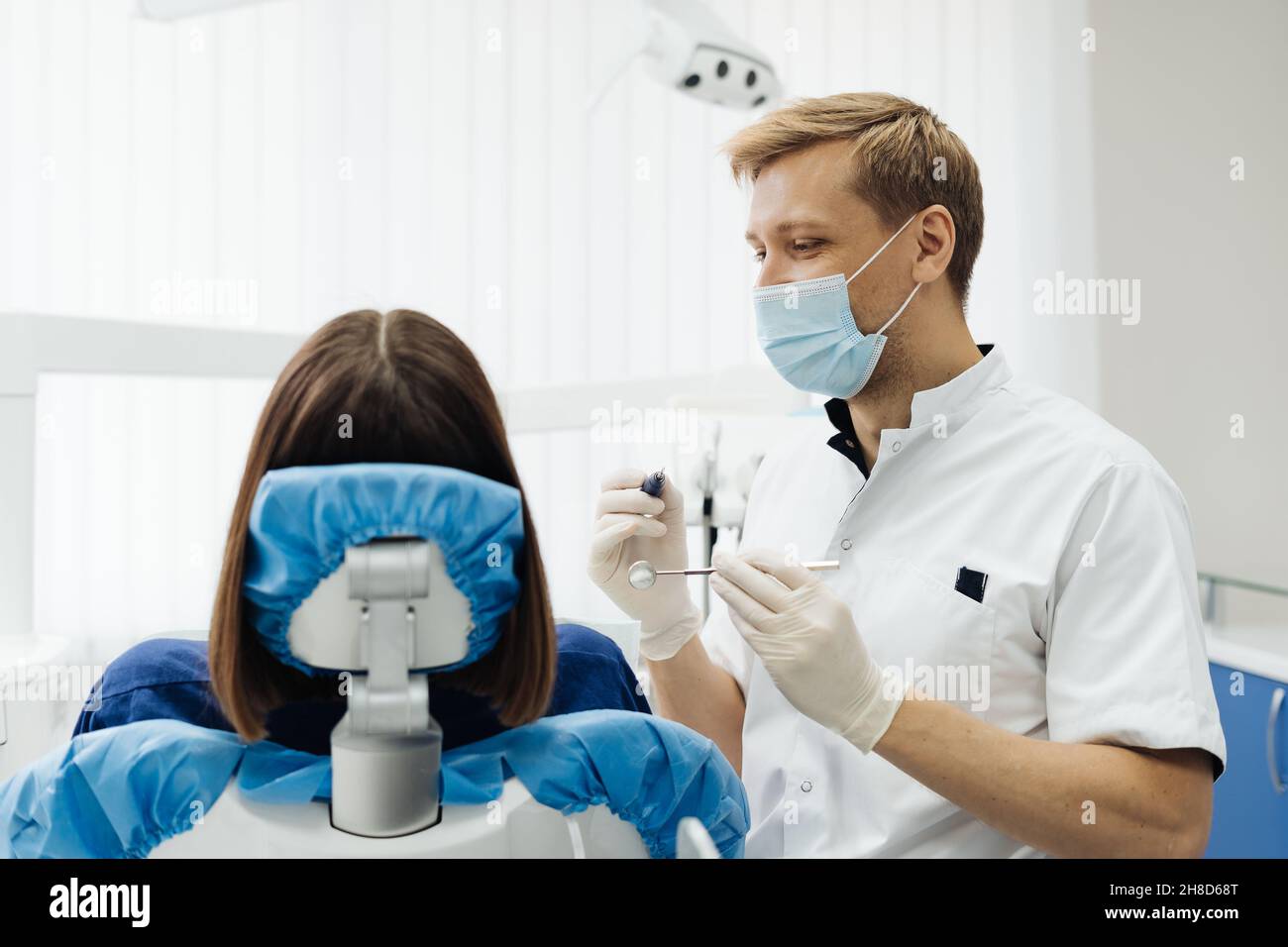 Caucasian male dentist examining young woman patient's teeth at dental ...