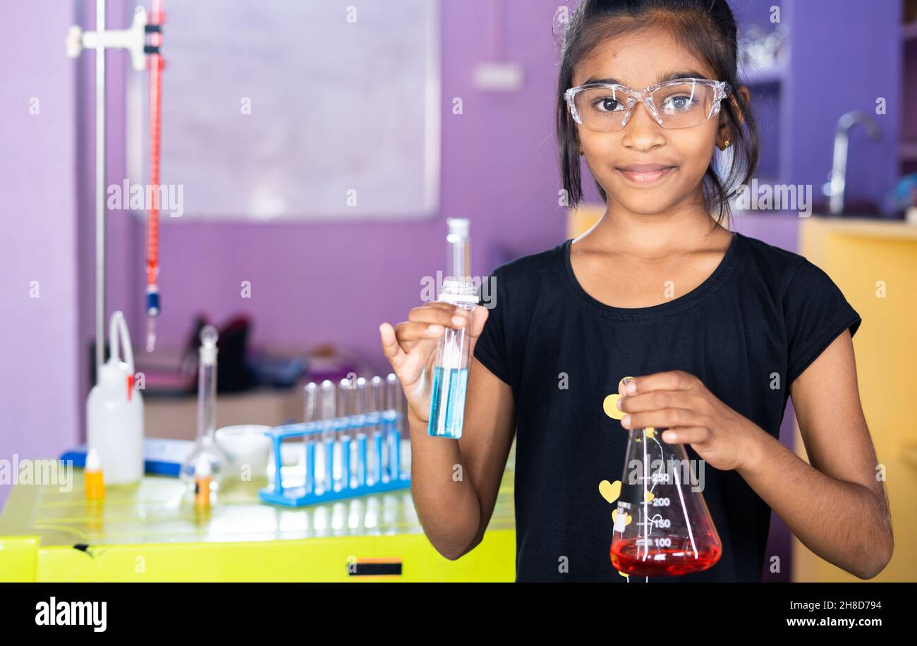 Happy confident school kid at science lab with chemical flask in hand ...