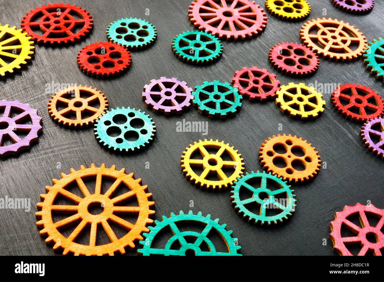 Multi-colored gear wheels on a dark surface. Variety and interaction ...