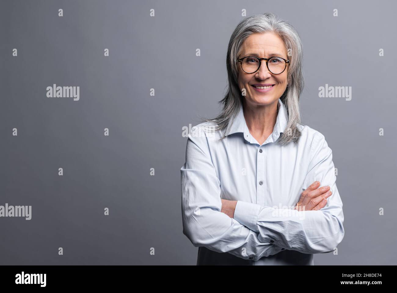 Successful senior mature gray-haired businesswoman with arms crossed ...