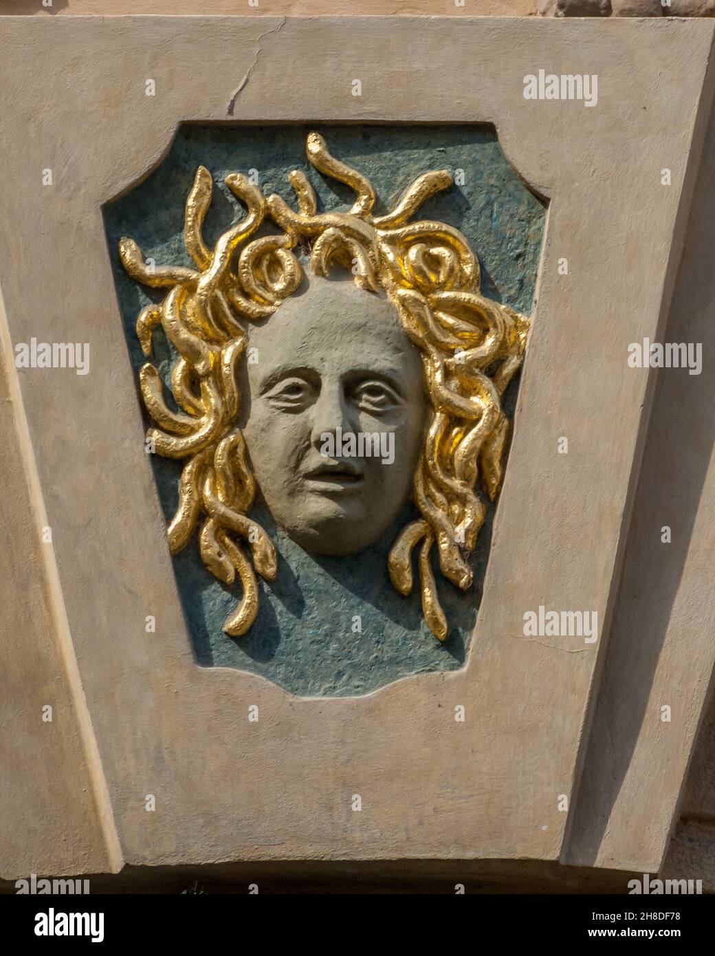 A petrified Medusa head with golden snake hair carved into the keystone ...