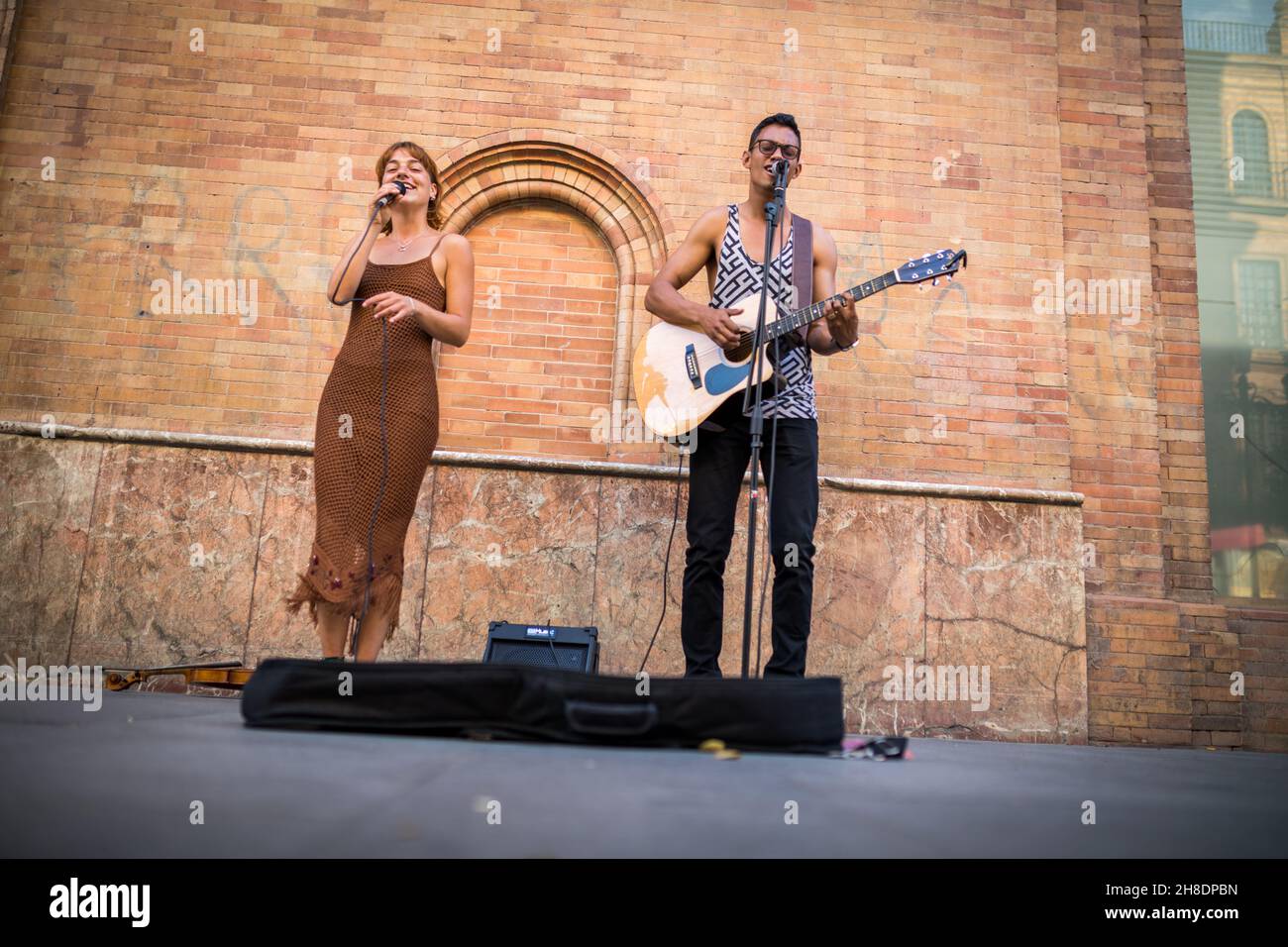 Buskers playing on a busy street in Seville, Spain. Guitarist man and ...