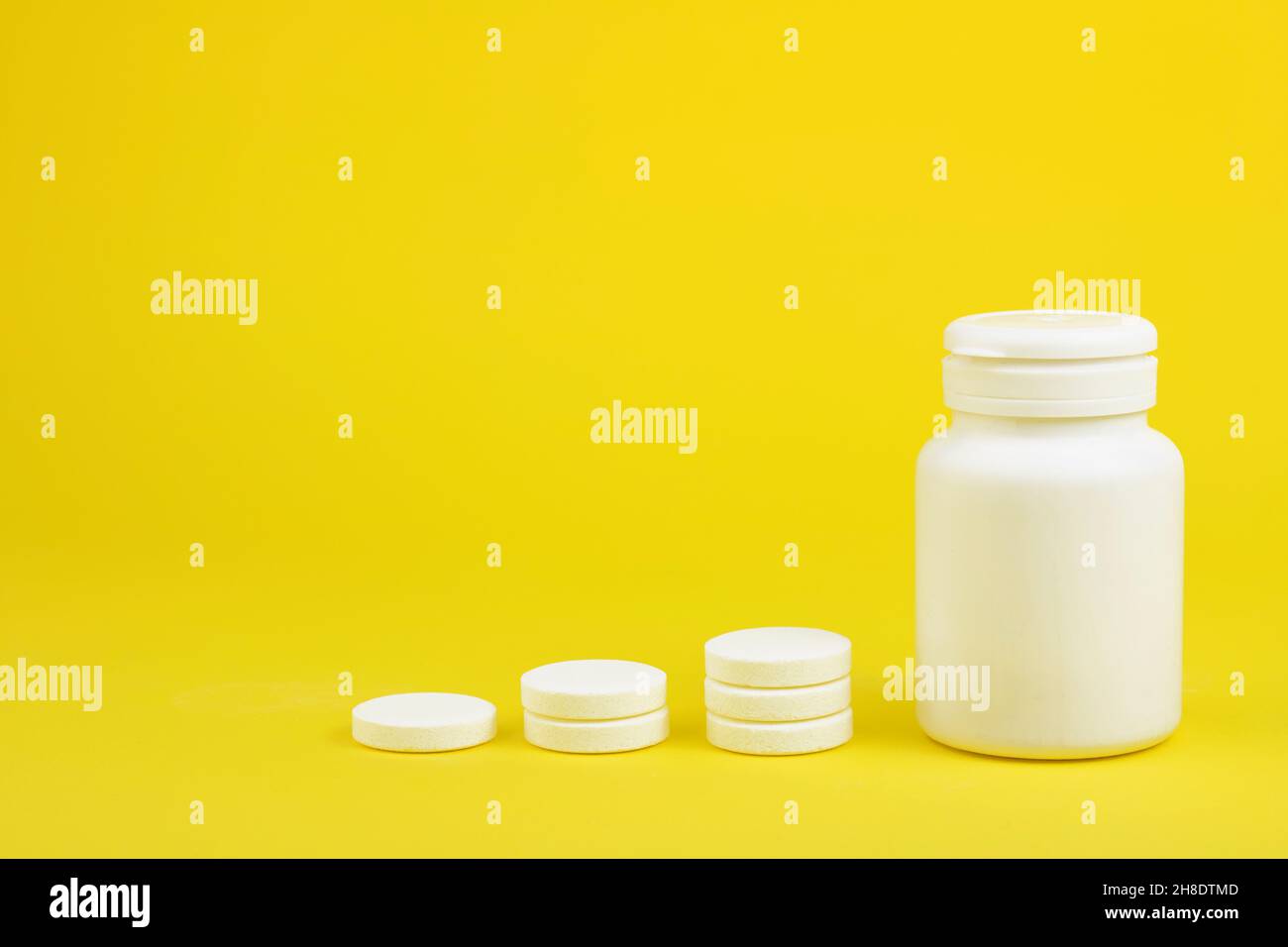 White soluble tablets near the bottle on a yellow background. The ...