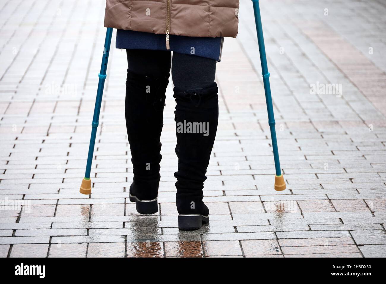 Woman walking with crutches on a city street, female legs on sidewalk ...