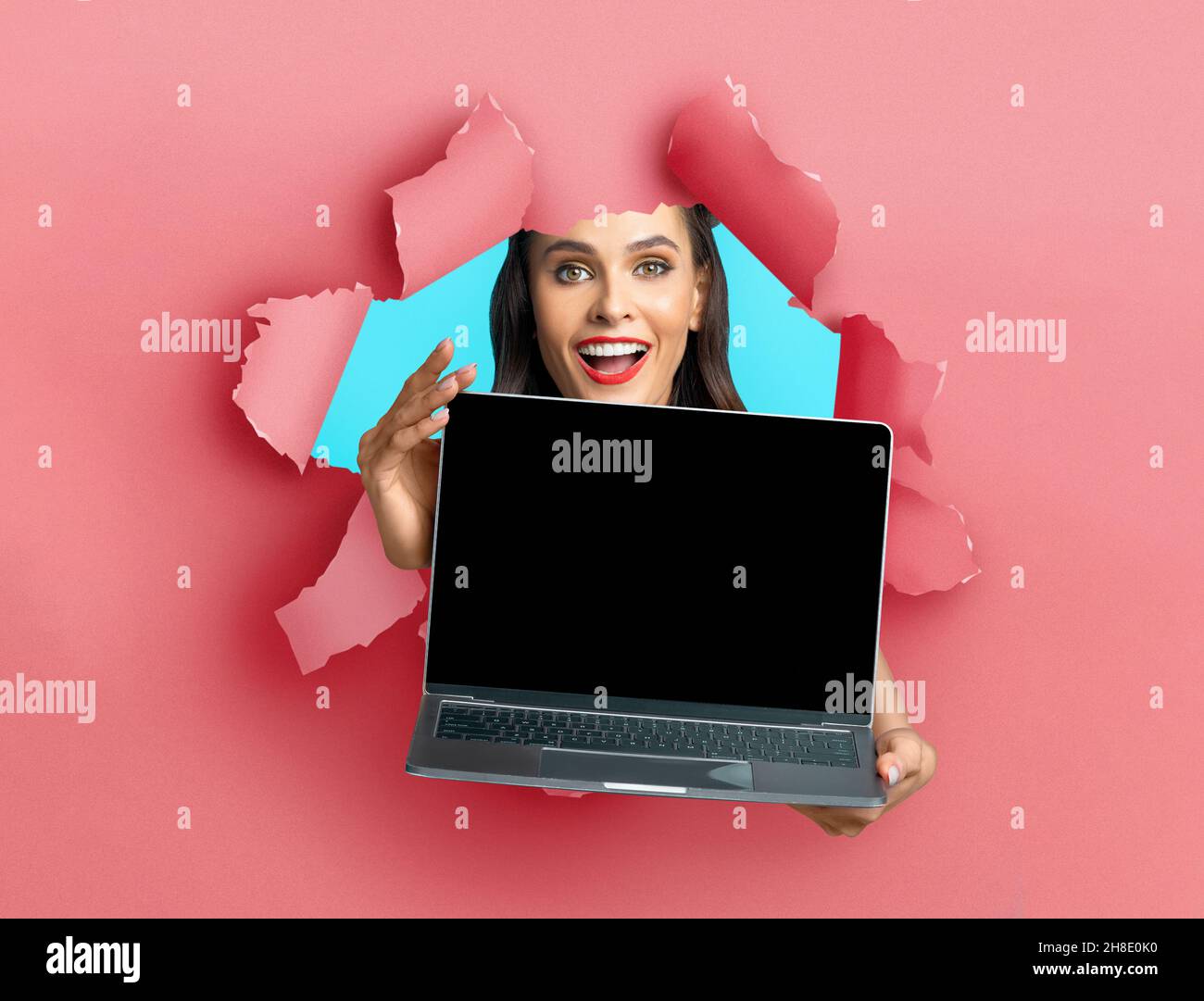 Young lady showing empty laptop screen through torn paper Stock Photo ...