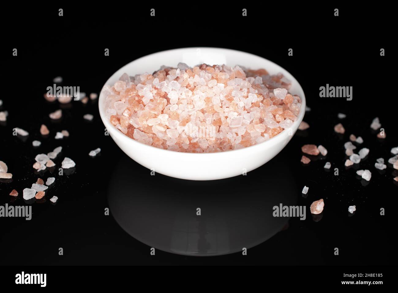 Rock salt of pink color in a white salt shaker, close-up, isolated on ...