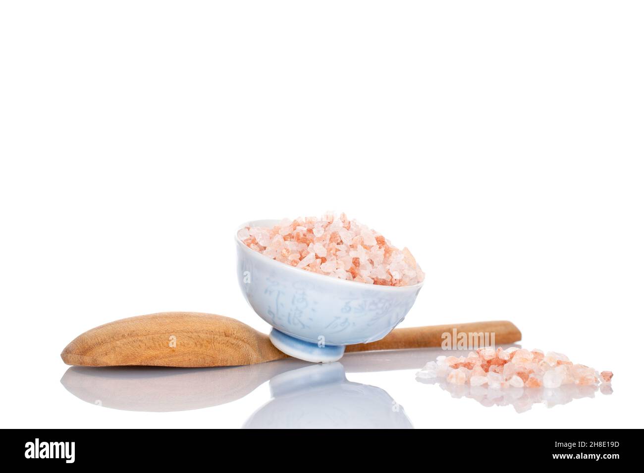 Rock salt of pink color with a wooden spoon and a ceramic salt shaker ...