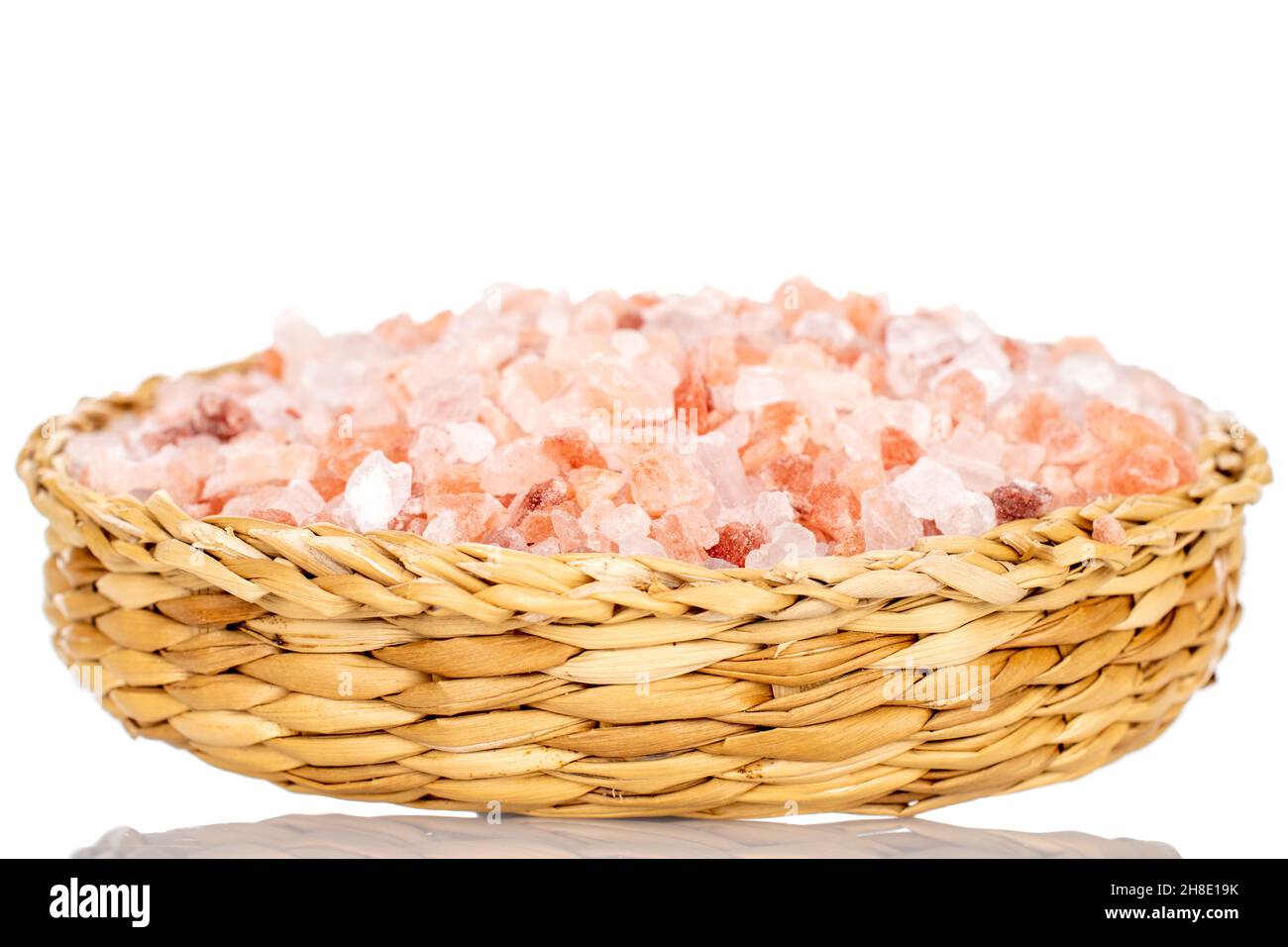 Rock salt of pink color in a straw salt shaker, close-up, isolated on ...