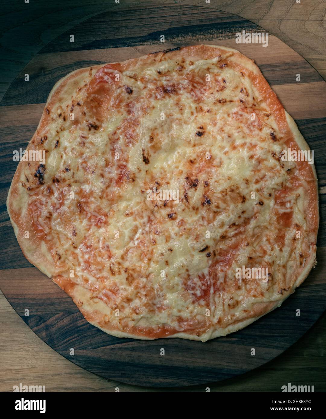 Homemade pizza on a round walnut board and oak table Stock Photo - Alamy