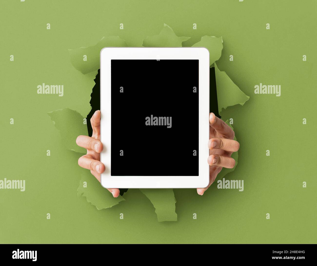 Person showing black empty tablet screen breaking through paper Stock ...