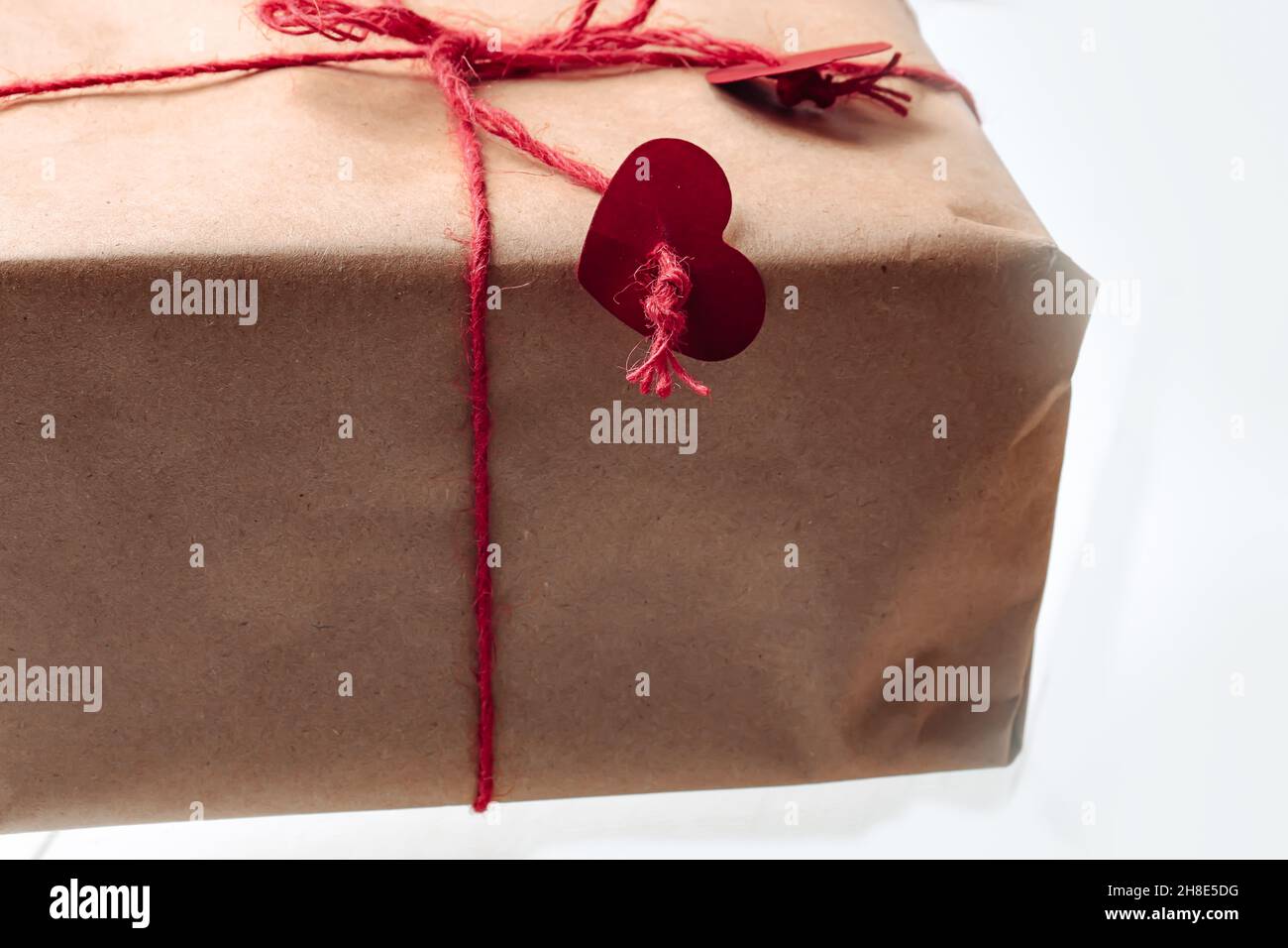 Gift box wrapped in kraft, tied with a rope with hearts. Eco-friendly ...