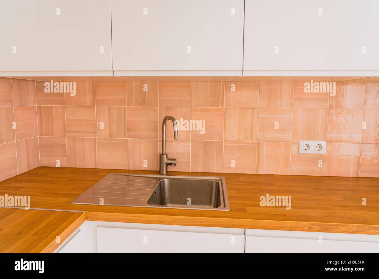 Modern kitchen interior with sink and chrome faucet, wood table top and ...