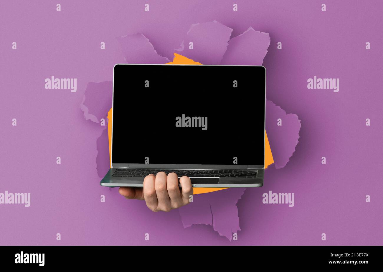 Person showing black empty laptop screen breaking through paper hole ...