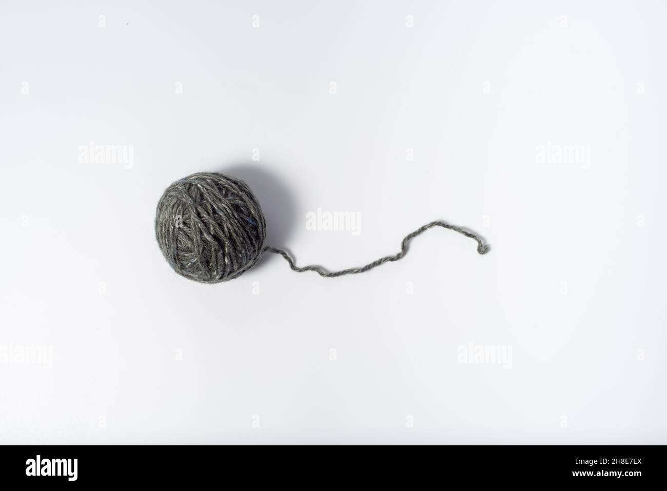 Dark grey ball of yarn with loose thread on white background Stock ...