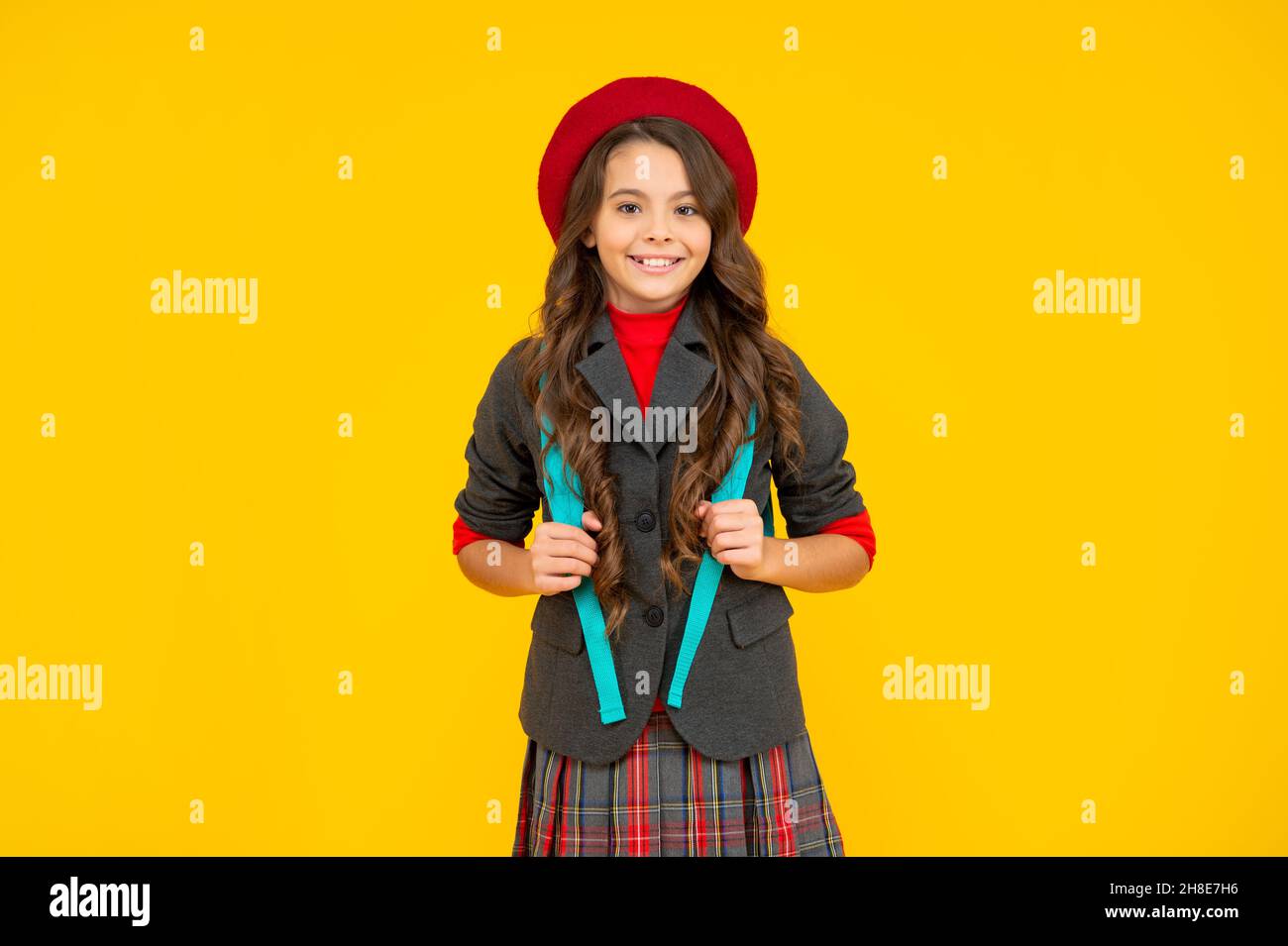cheerful kid in school uniform with beret and backpack on yellow ...