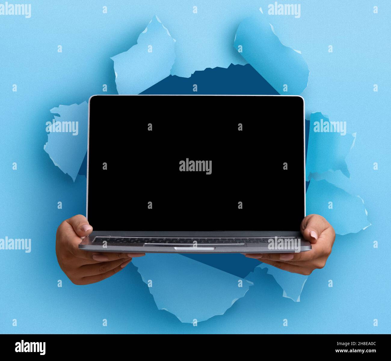 Person showing black empty laptop screen breaking through paper Stock ...