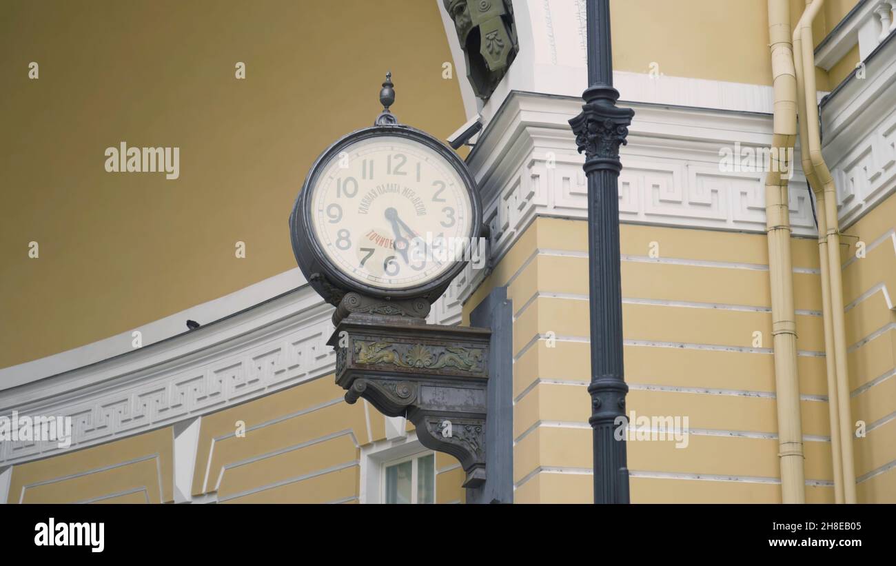 Old clock on facade of yellow building. Action. Street clock protrudes ...