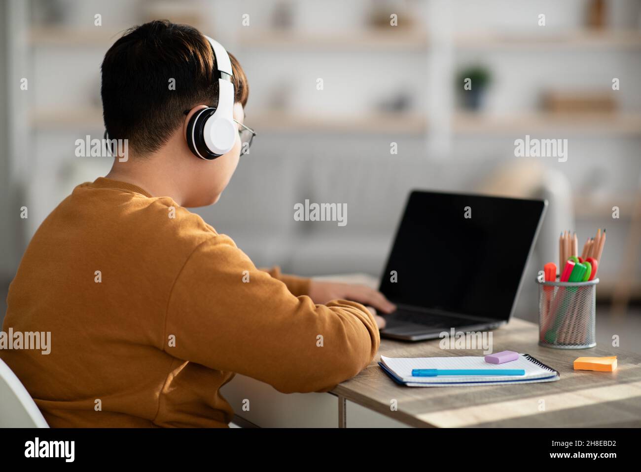 Chinese kid using laptop with empty screen and headset Stock Photo - Alamy