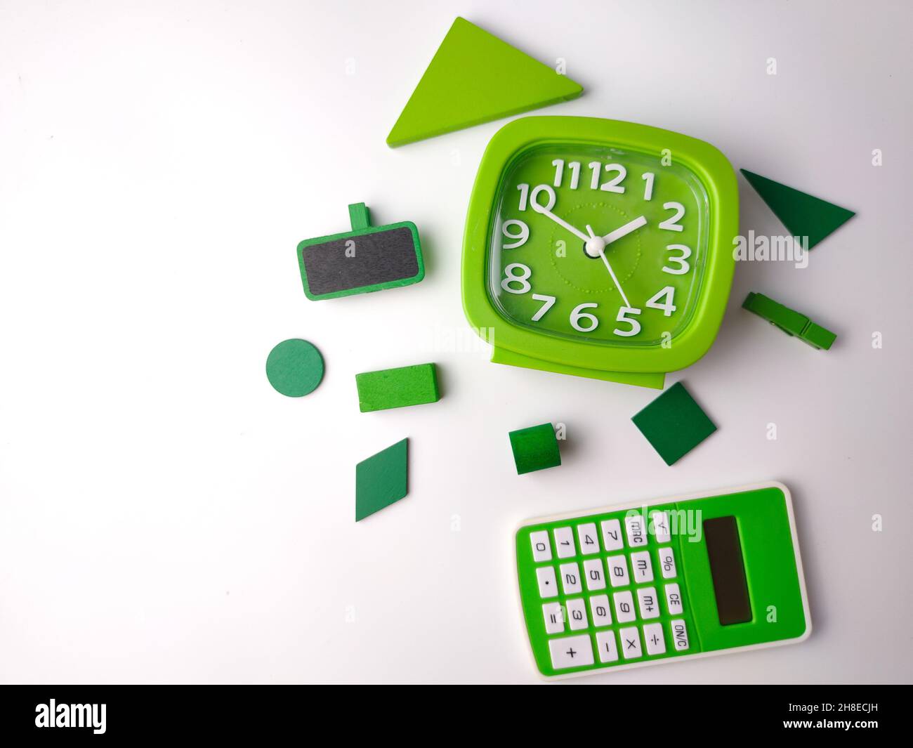 Top view of a green alarm clock, calculator, and geometric shapes on a ...