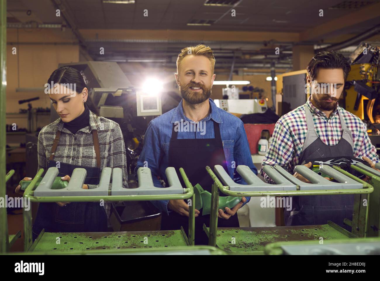 Three different shoe factory workers work together on the same machine ...